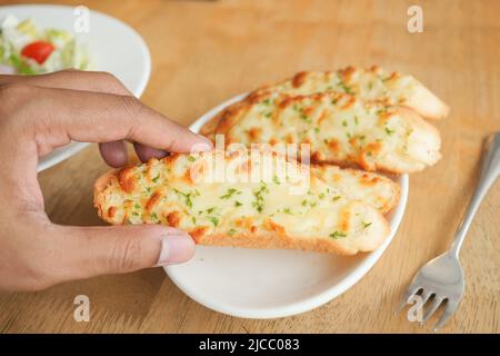 hand pick a garlic bread on a plate Stock Photo - Alamy