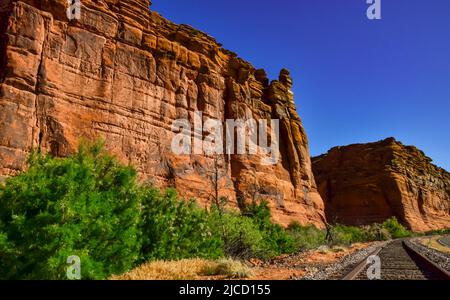 Railroad at the bottom of a canyon next to Layered Geological ...