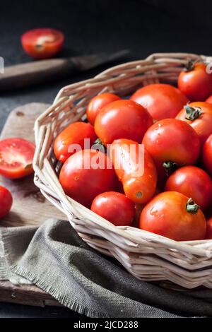 Fresh red tomatoes in whicker basket on black background Stock Photo ...