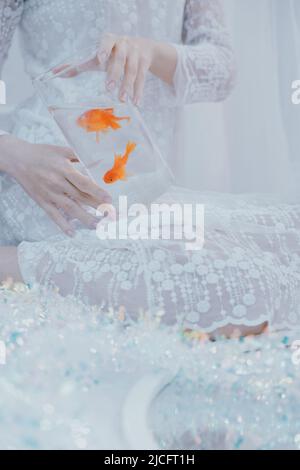 Girl with goldfish in white Stock Photo - Alamy