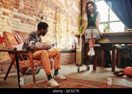 Interracial couple sitting on a armchair and kiss one another. Woman ...
