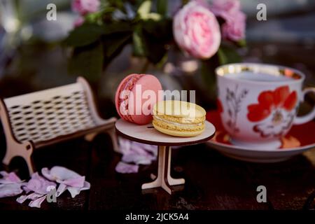 French macarons on the wooden miniature table near bench in cafe style ...