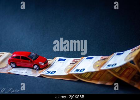 small red car toy on 50 euro banknotes on black background Stock Photo ...