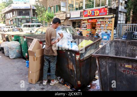 Boy digs into the garbage in a street of Beirut, Lebanon, June 13 2022 ...