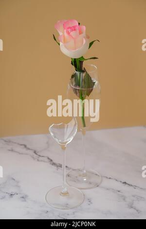 Broken champagne glass with Delicate pink rose on beige background ...