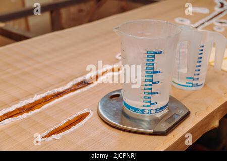 Liquid cup with epoxy resin on a wooden table. Process of making a ...