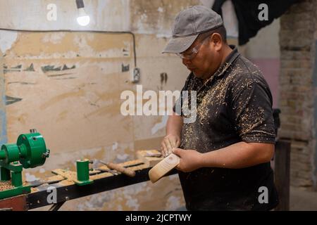 Closeup of person sanding wooden product using sandpaper on a lathe ...