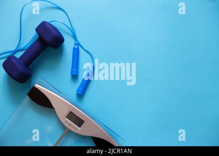 Flat lay composition with weigh scales, skipping rope and dumbbells ...
