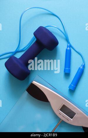 Flat lay composition with weigh scales, skipping rope and dumbbells ...
