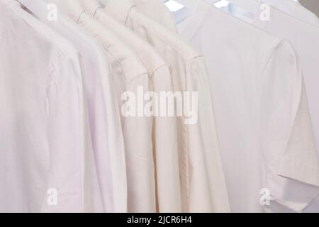 White clothes closeup hanging on white hangers Stock Photo - Alamy