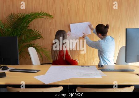 Back workers with architectural sketches and technical plans in office ...