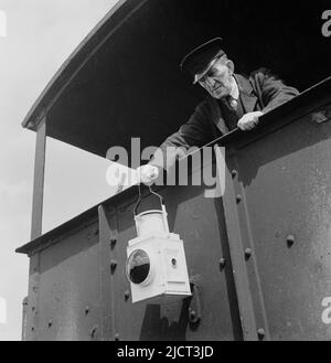 1950s, historical, a uniformed train guard in the open rear of a ...