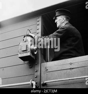 1950s, historical, a uniformed train guard in the open rear of a ...