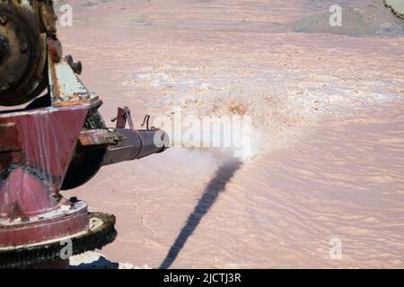 Foamy muddy water gushes out of the pipe under high pressure. Discharge ...
