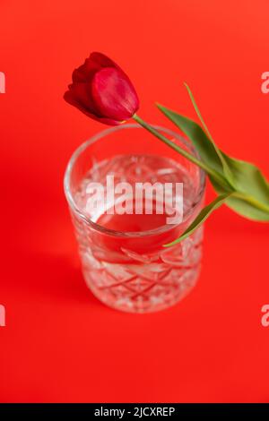 glass with faceted pattern and pure water on grey blurred background ...