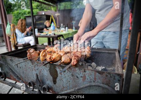 Man frying shish kebab on barbecue grill, open fire on a summer day in ...