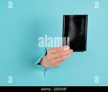 A woman's hand sticks out of a blue paper background and holds a ...