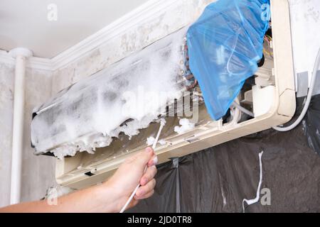 A man sprays special foam to clean air conditioners on the radiator ...