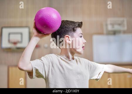 Boy throwing ball during PE class in school gym Stock Photo - Alamy