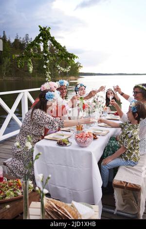 Family raising toast during midsummer dinner by lake Stock Photo - Alamy