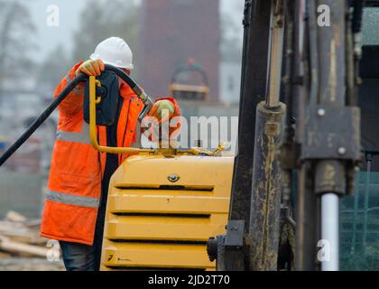 Construction worker in safety gloovs filling excavator with diesel fuel ...