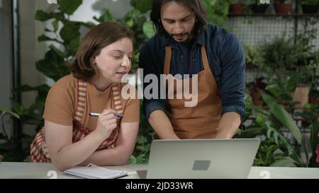 Small business employees checking online orders in front of laptop ...