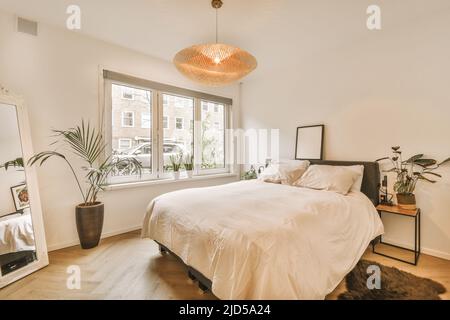 Comfortable bed located near glowing lamp and framed pictures in ...