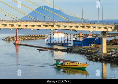 Manado port and Soekarno Bridge with Manadotua Island beyond at sunset ...