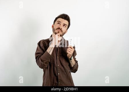 Thoughtful guy holding plastic credit card and thinking, looking ...