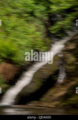 View of blurry waterfalls and trail in Hafod Uchtryd wooded and ...