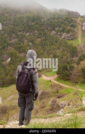 A man and a Pembroke Welsh Corgi climb above the clouds high in the ...