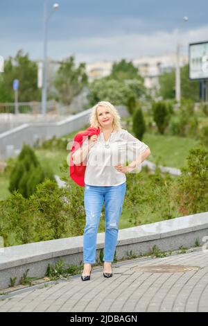 With a jacket slung over her shoulder, female teen smiles gently and ...