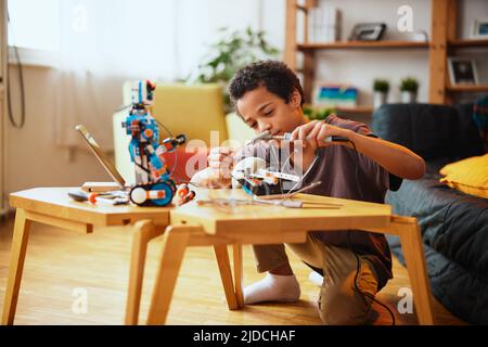An African-American boy making a robot at home. Education in robotic at ...