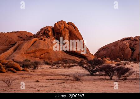 Bold rock formations glowing bright orange in the last rays of the ...