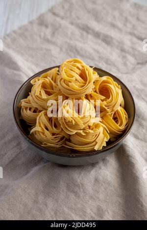 Homemade Organic Dry Tagliatelle Pasta in a Bowl, low angle view. Copy ...