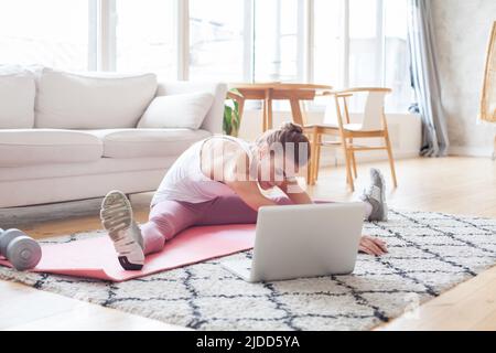 Beautiful young woman repeating exercises while watching online ...