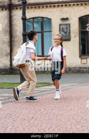 Cheerful boy talking to a friend on the phone and looking interested ...
