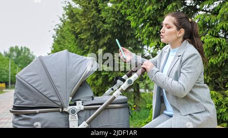 Woman checks social networks rocking baby in stroller Stock Photo - Alamy