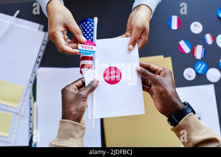 Top view of hands holding voting ballot and sticker on election day ...