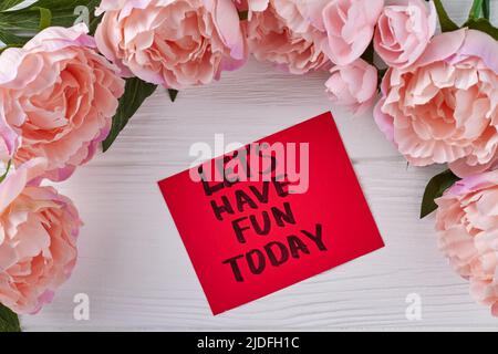 Red paper with lets have fun handwriting. Arrangement of pink peony ...