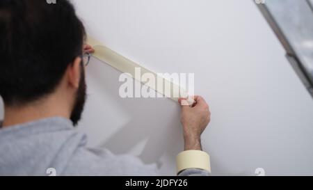 Home repair master using masking tape before painting Stock Photo - Alamy