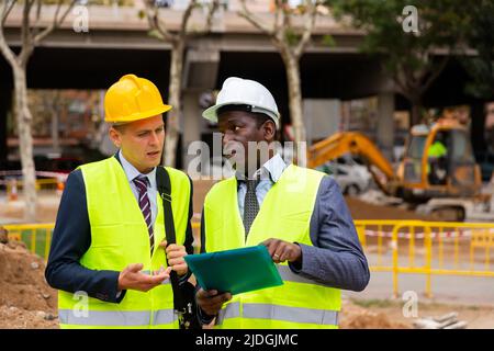 Two engineers talking about road repairing works documentation Stock ...