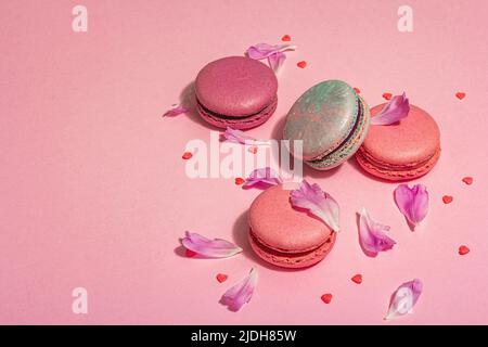 Macarons with peonies flower petals on pink background. Sweet dessert ...