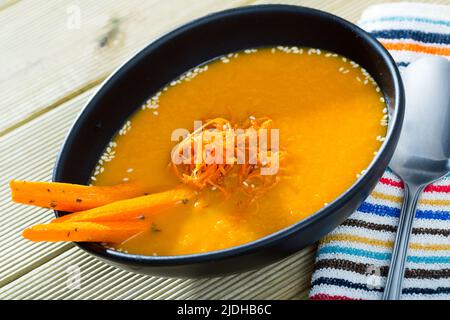 Tasty boiled vegetarian carrot cream soup served at plate on table ...