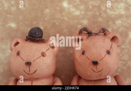 Two small clay model teddy bears standing side by side with one wearing ...