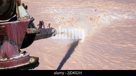 Foamy muddy water gushes out of the pipe under high pressure. Discharge ...