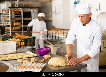 Concentrated baker preparing sweet buns in bakery Stock Photo - Alamy