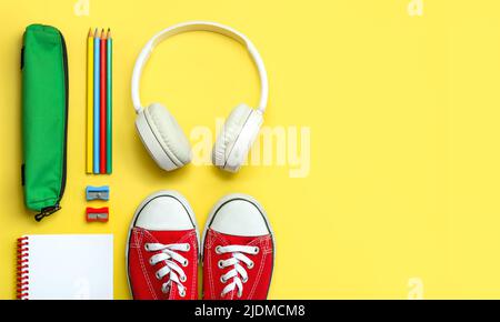 Yellow backpack with school stationery and headphones on bench outdoors ...