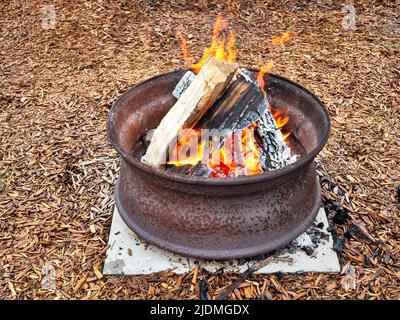 Campfire in a steel wheel on the concrete base and green lawn Stock ...