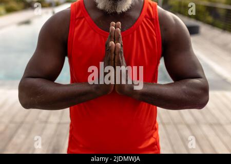Midsection of african american senior man meditating in prayer position ...
